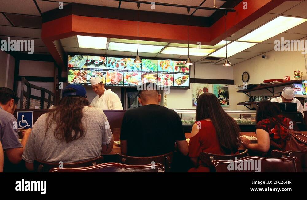 Sushi restaurant people sitting in front of counter facing chef ...
