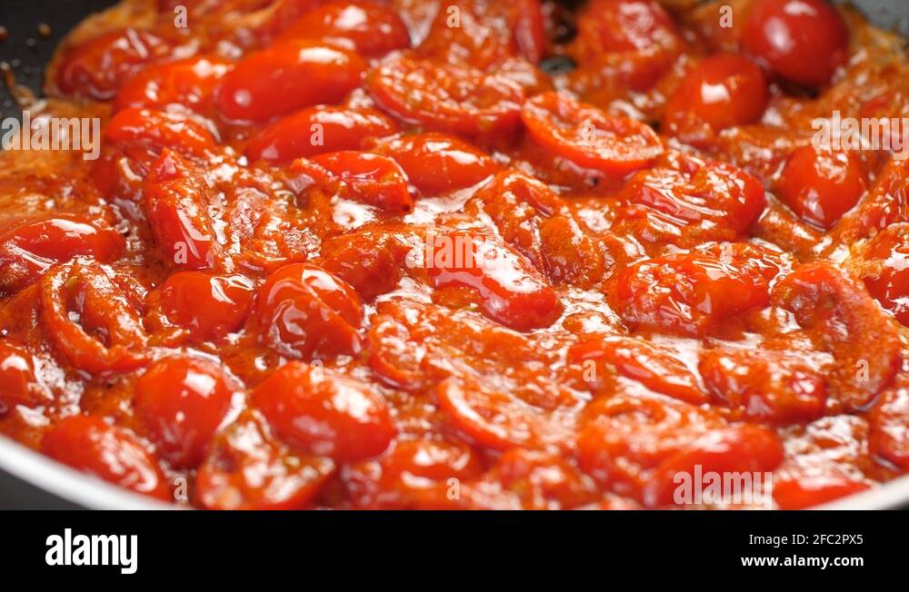 Thick tomato sauce bubbling in hot pan, wooden spatula splitting sauce ...