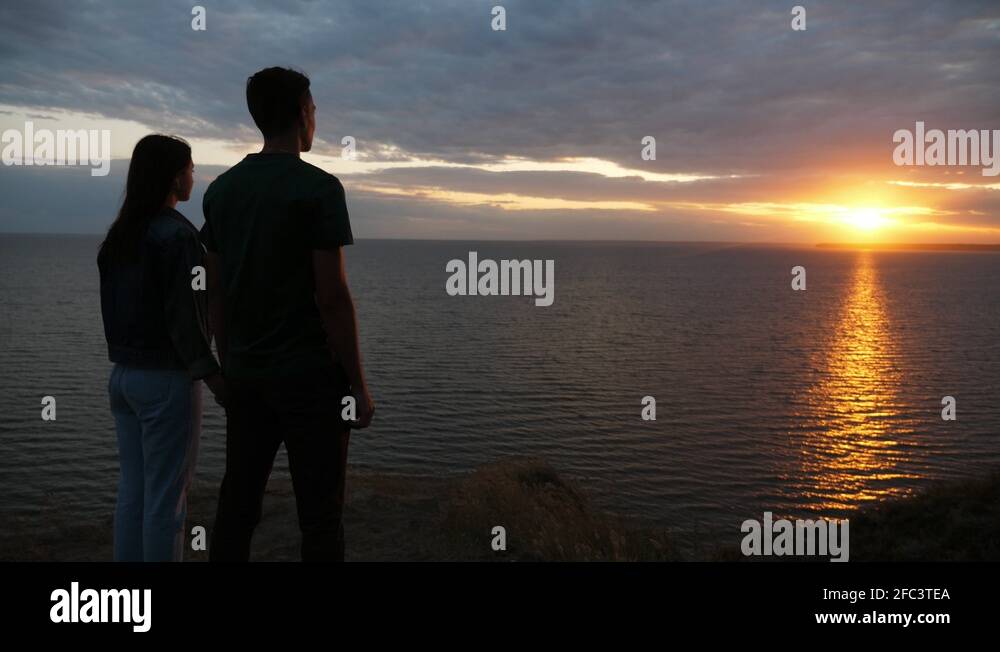 Romantic boy and his beauty look at future at the Black Sea at sunset ...