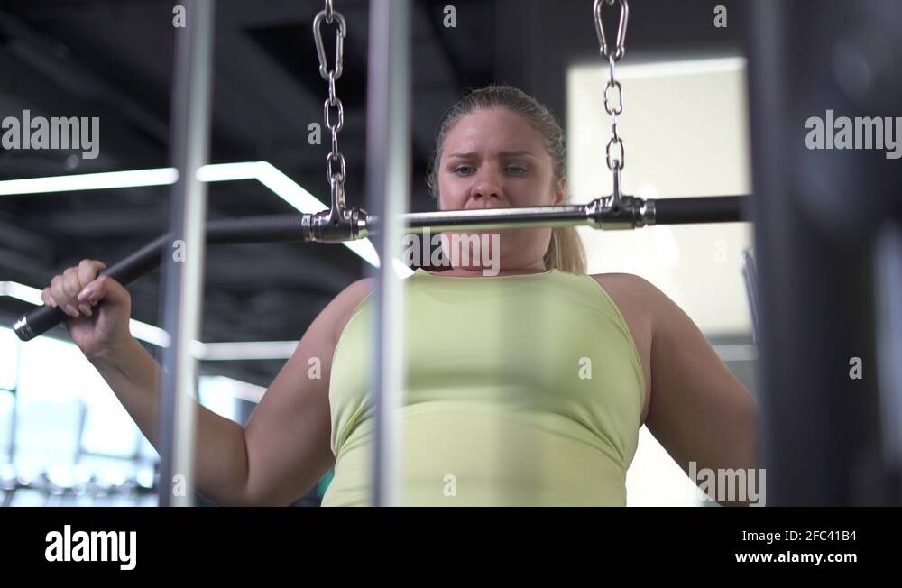Plus Size Model, woman trains in Gym, lifting blocks on rack machine ...