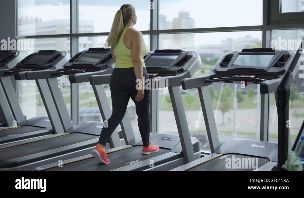 Young Plus Size Model, woman walking on a treadmill in gym near ...