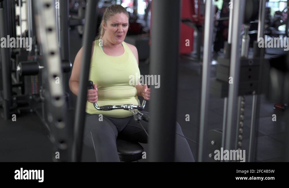 Plus Size Model, woman trains in Gym, lifting blocks on rack machine ...