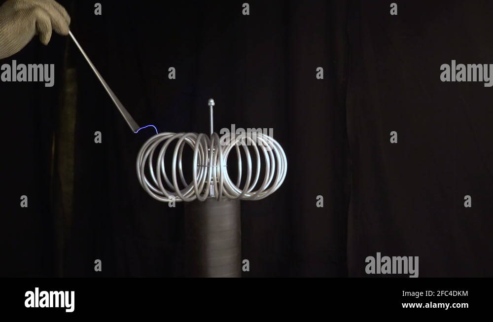 Man hand hold metallic part coil create blue electric spark black ...