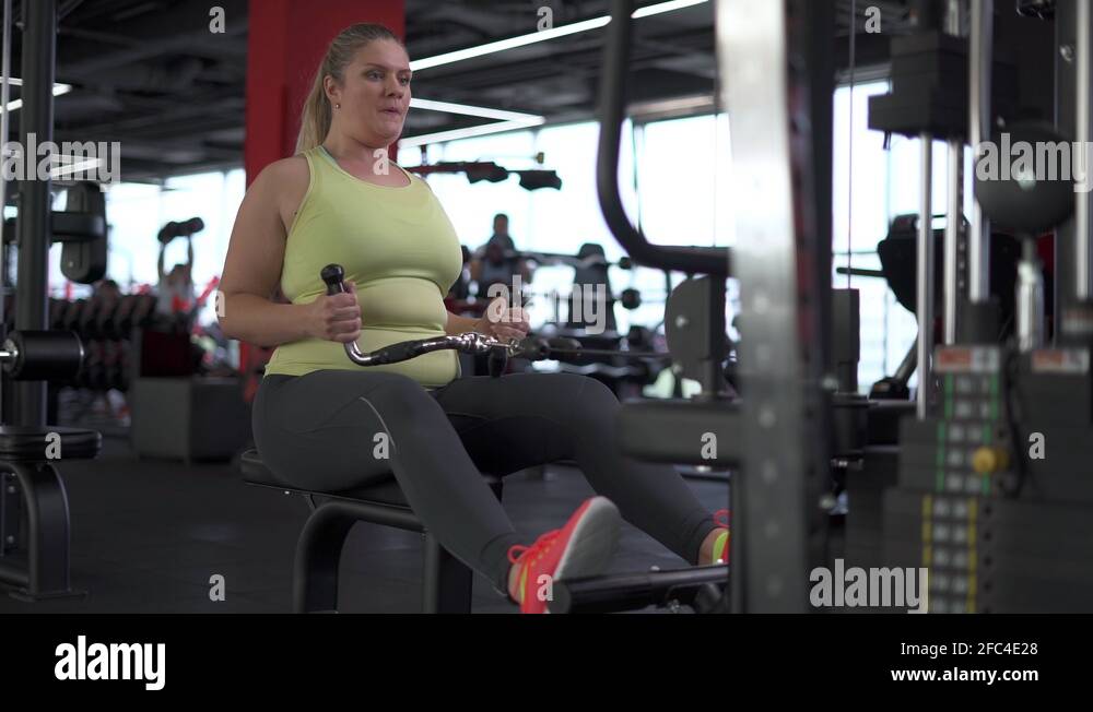 Plus Size Model, woman trains in Gym, lifting blocks on rack machine ...