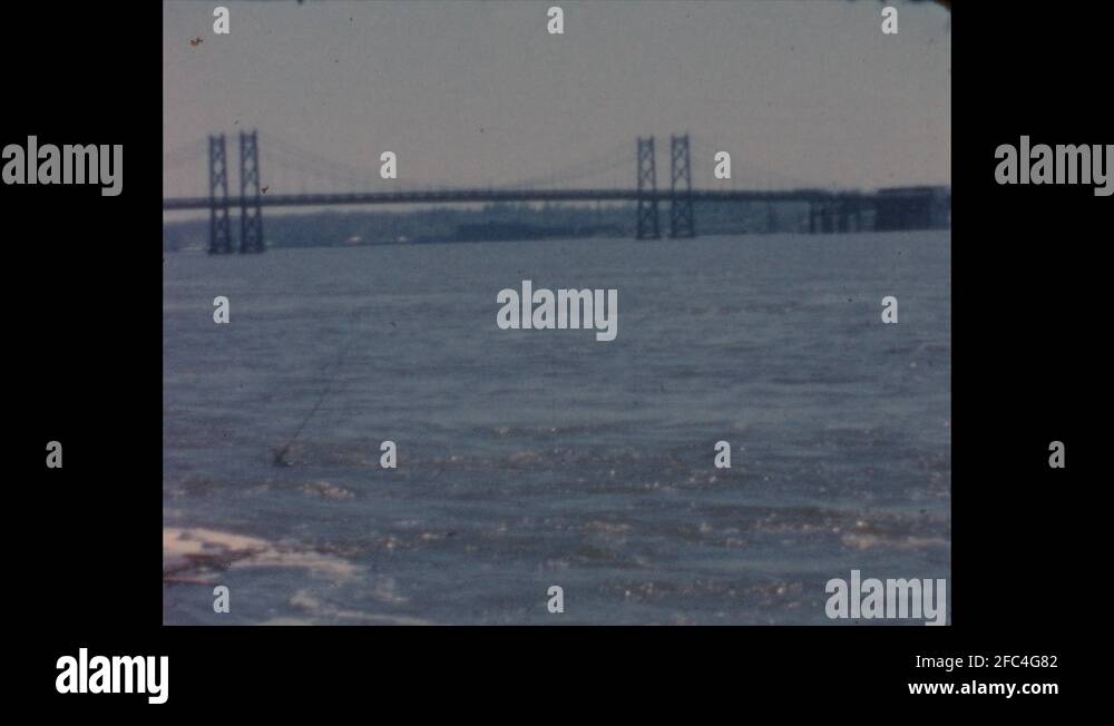 1940s: UNITED STATES: bridge across water. Burst banks on river ...