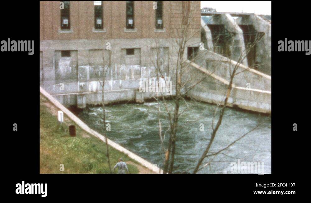 1940s: Water passes through dam. Woman and girl stand near reservoir ...