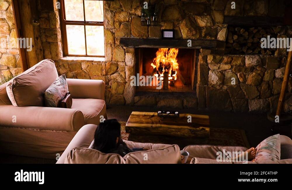 A young woman relaxing in front of a roaring fire in winter Stock Video ...
