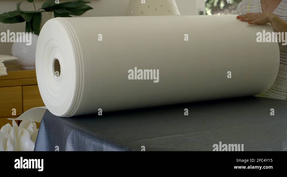 woman is unrolling large roll with white fabric on table in fabric ...