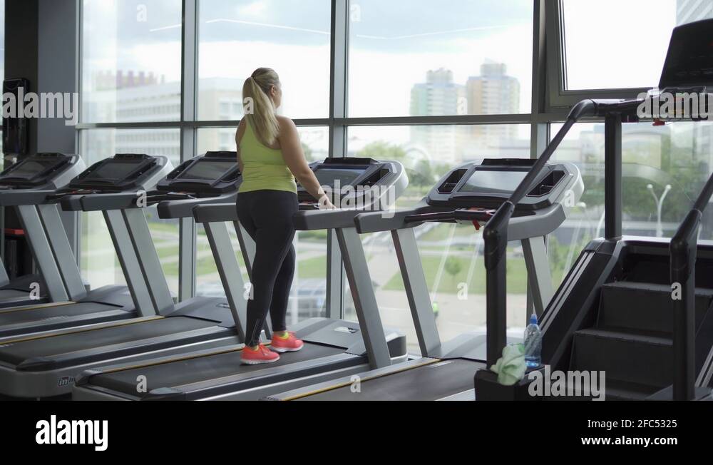 Young Plus Size Model, woman walking on a treadmill in gym near ...