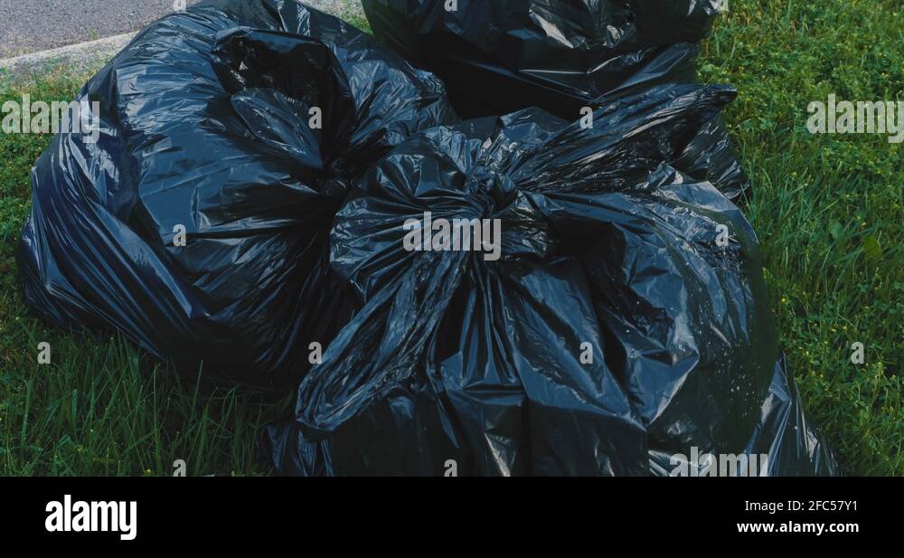 Pile of black, plastic garbage bags put out on the curb for collection ...