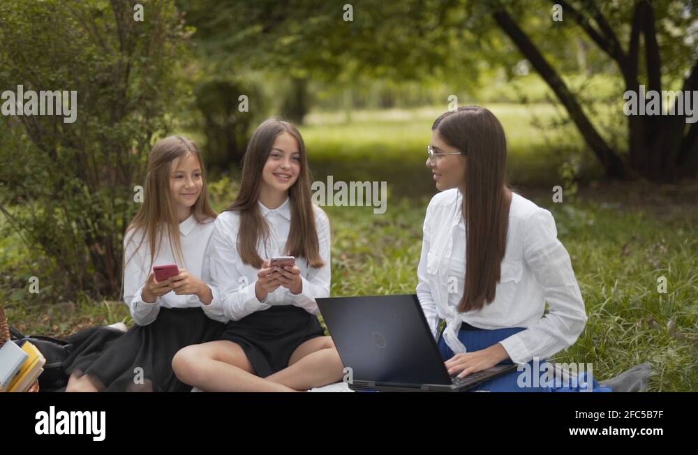 Teacher using laptop trying to teach two distracted school girls using ...