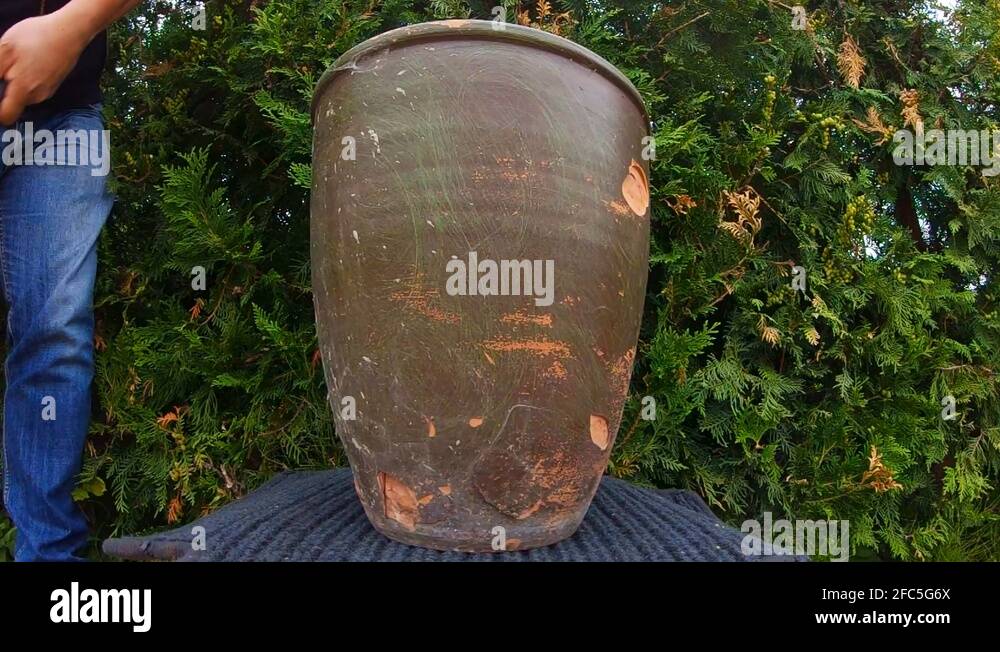 A man with a black metal hammer smashed an empty ceramic flower pot ...