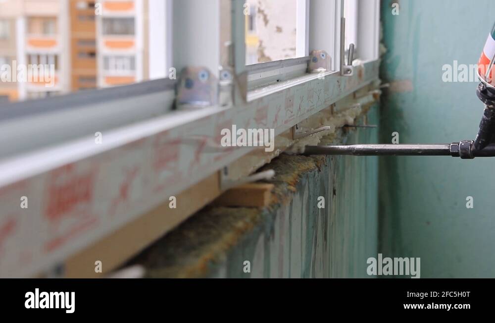 Worker is applying polyurethane foam to fill gap between sash and ...