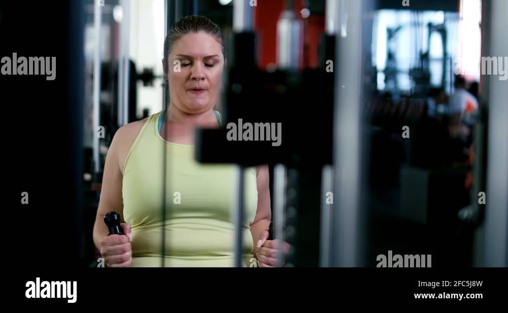 Plus Size Model, woman trains in Gym, lifting blocks on rack machine ...