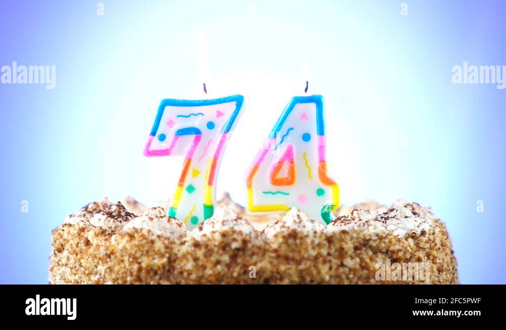 Birthday cake with a burning birthday candle. Number 74. Background ...
