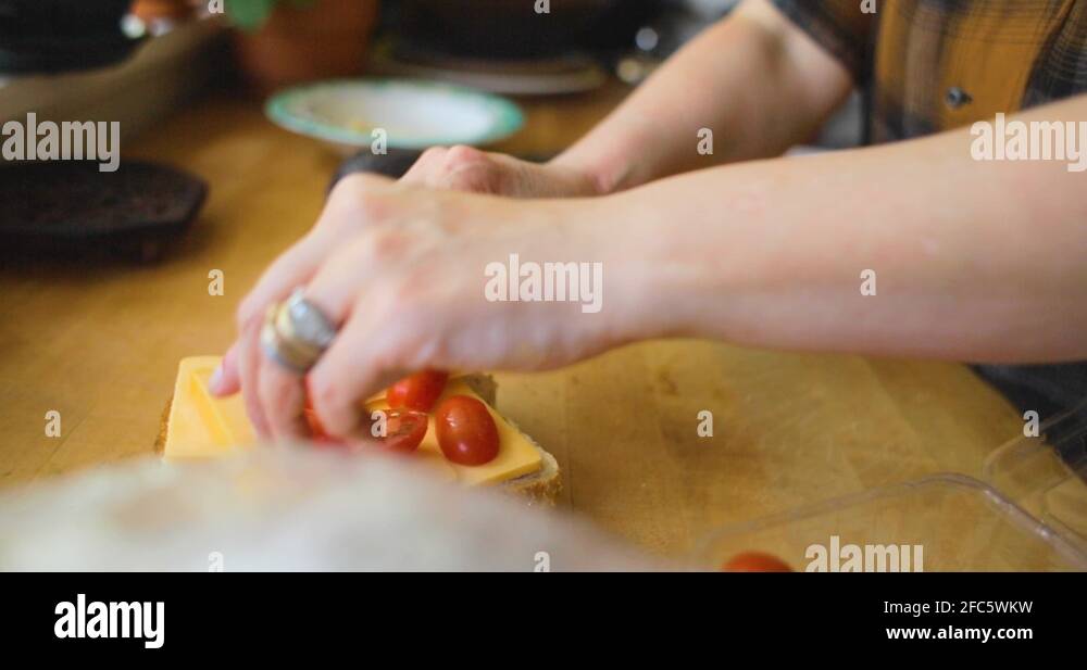 Old woman makes cheese and tomato sandwich in a kitchen for lunch Stock ...