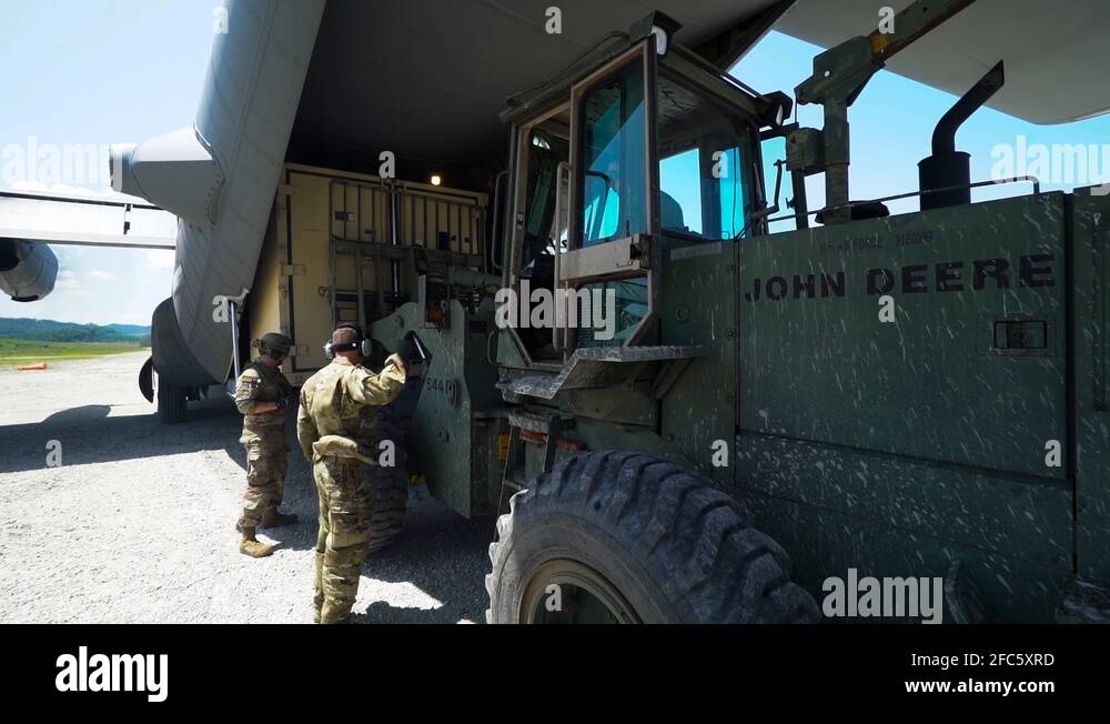 Loadmasters pushing steel container onto C-130 Hercules from forklift ...