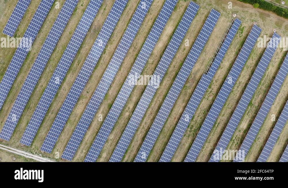 Top down view flying across perfectly aligned solar panels part of ...