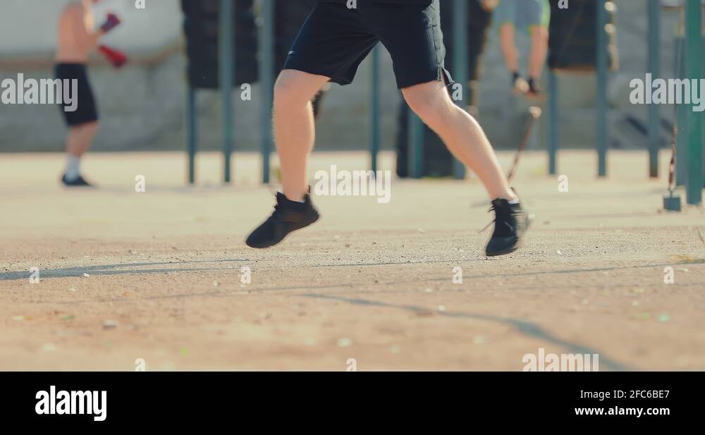 Athlete trains leg technique on a street playground. Athlete's legs are ...