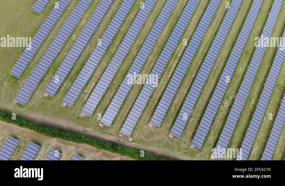 Top down view flying across perfectly aligned solar panels part of ...