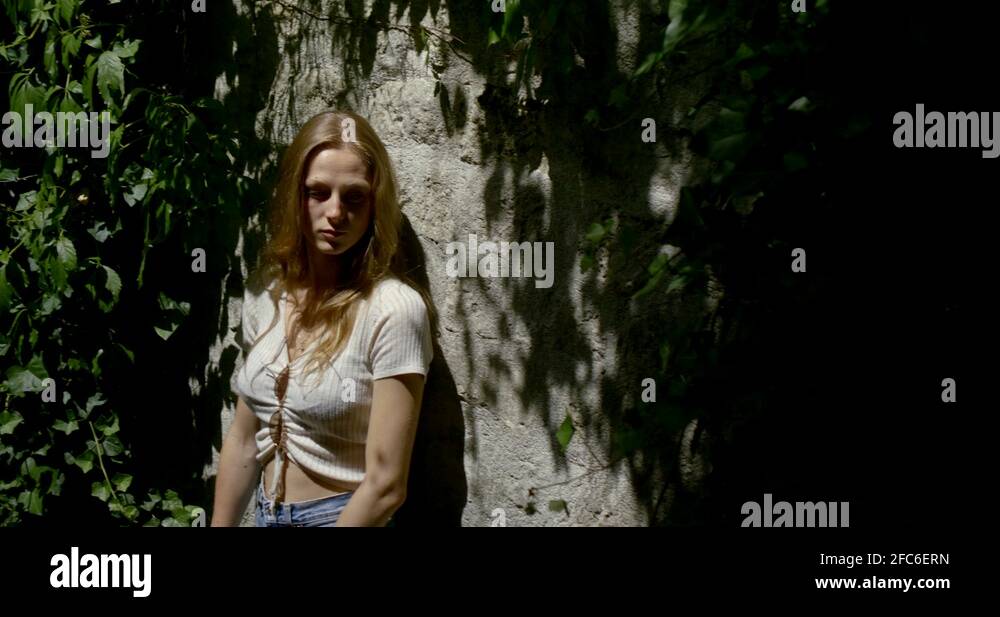 Portrait of a young blonde girl model who leaned against a tree among ...