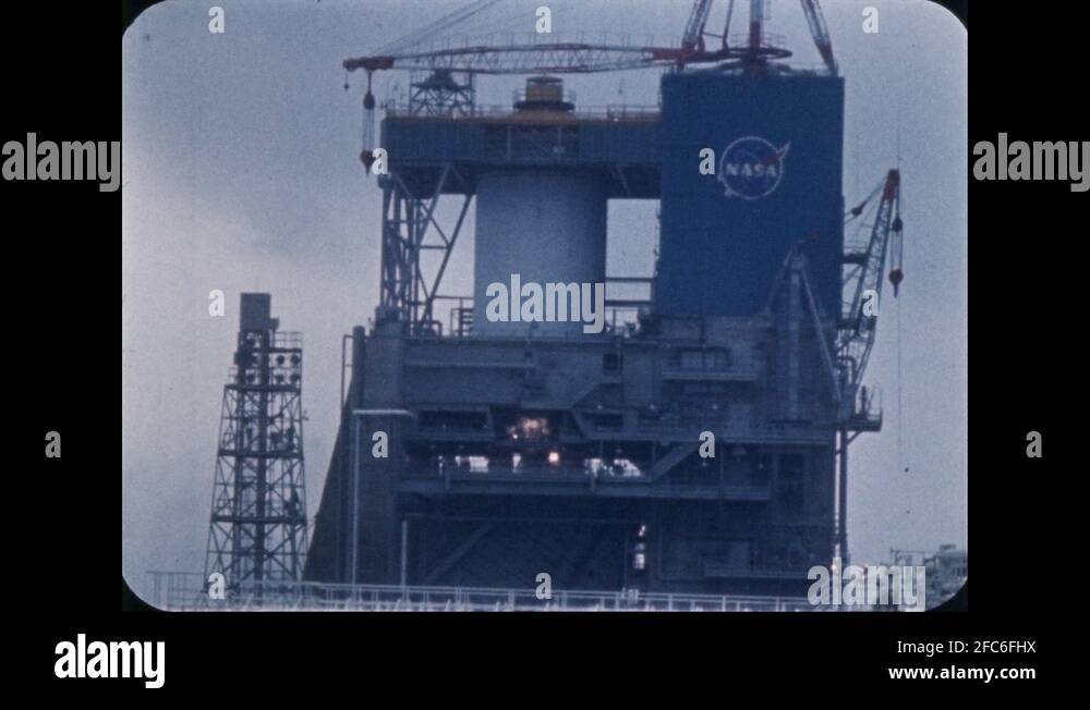 1960s: Exterior of NASA facility, with rocket emitting exhaust and ...