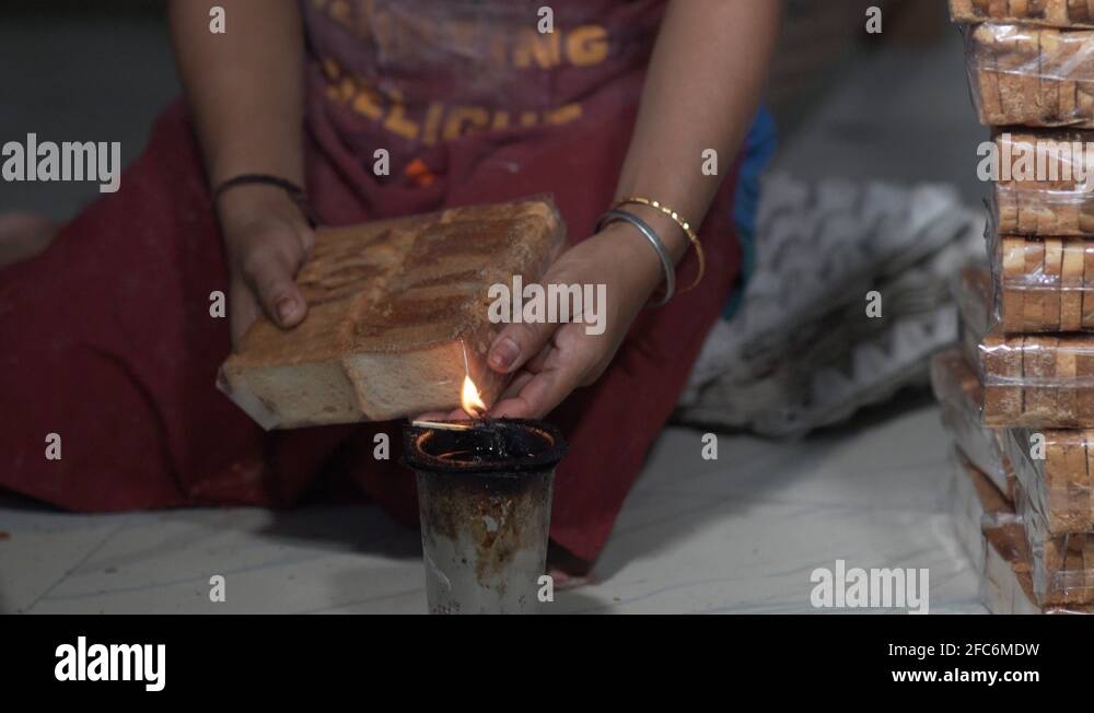 A bakery worker in India closing the plastic packaging on the bread bag ...