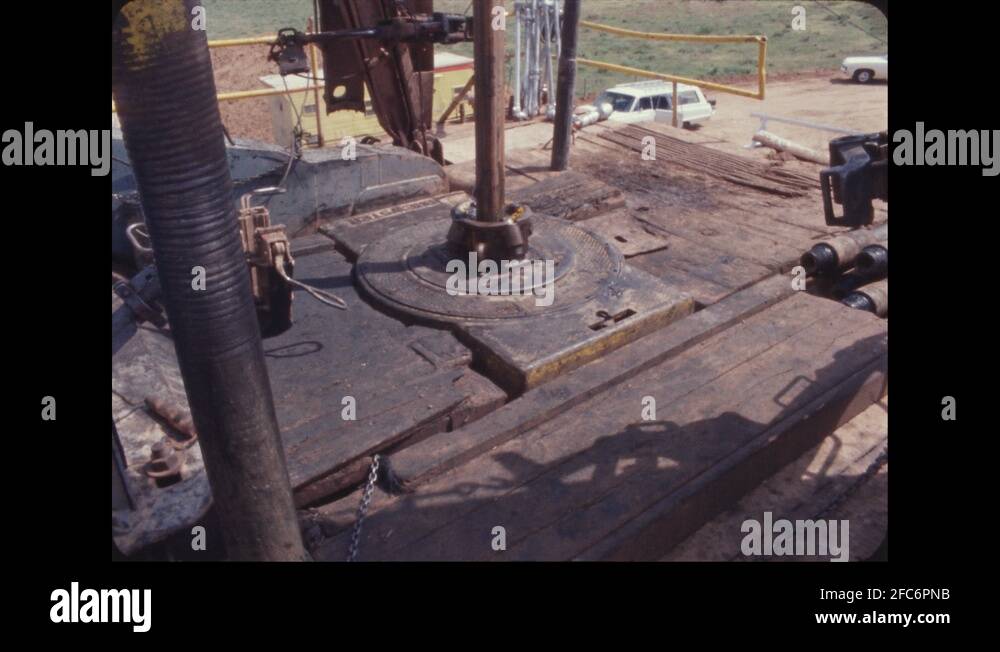 1960s: Drill turning on oil rig, tilt up tower. Low angle view of tower ...