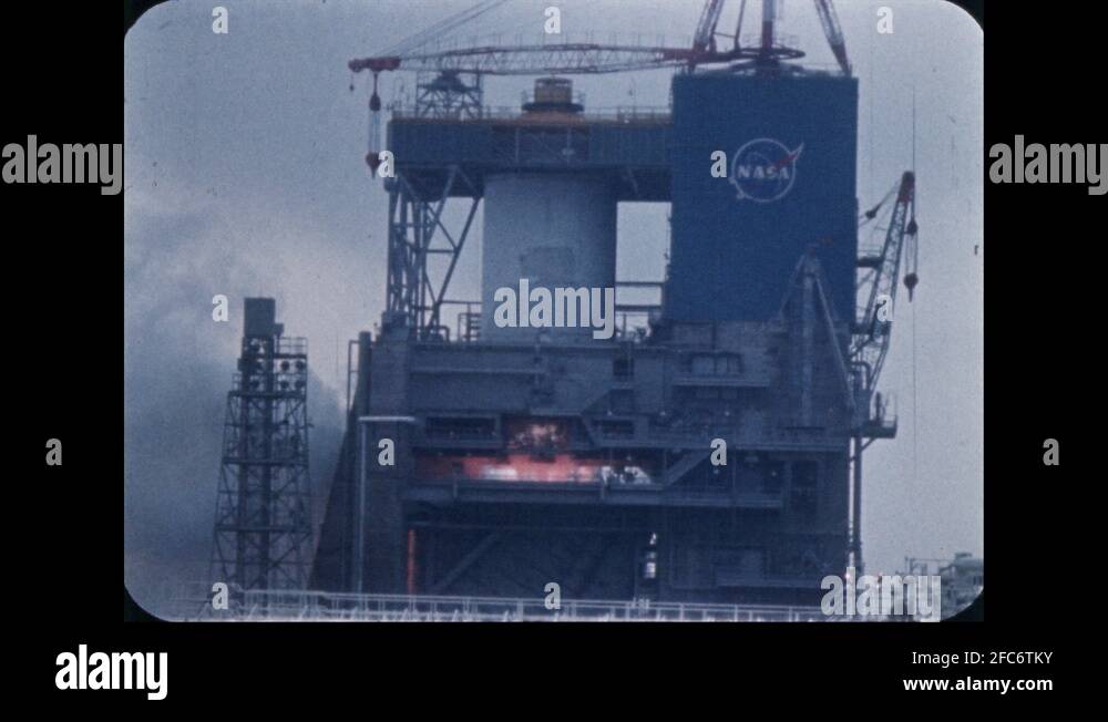 1960s: Exterior of NASA facility, with rocket emitting exhaust and ...
