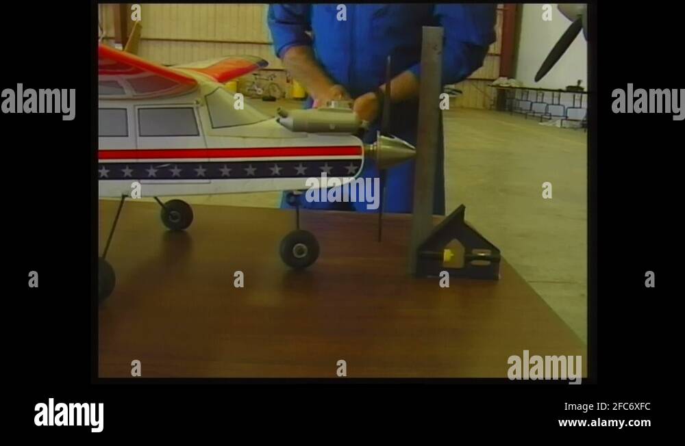 1990s: Man measuring parts of model plane. Hands measure wheels of ...