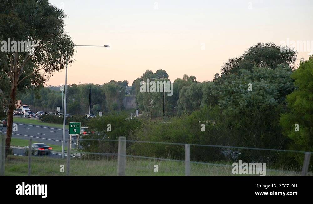 Australian motorway traffic and an exit sign seen through a gap in the ...