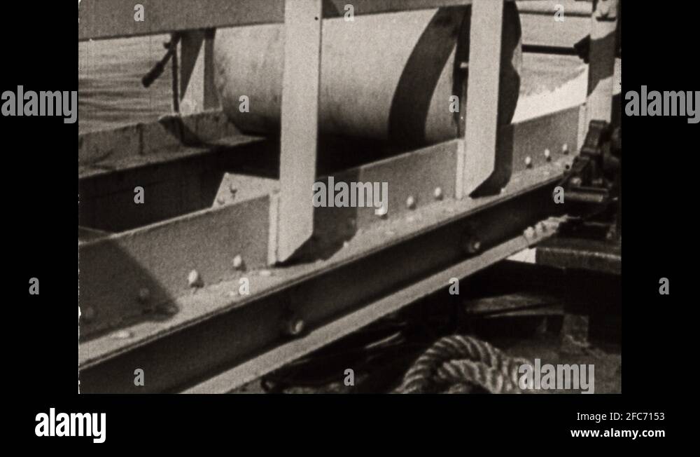 1940s: Tank rolling off of ship. Men on ship deck. View from ship ...