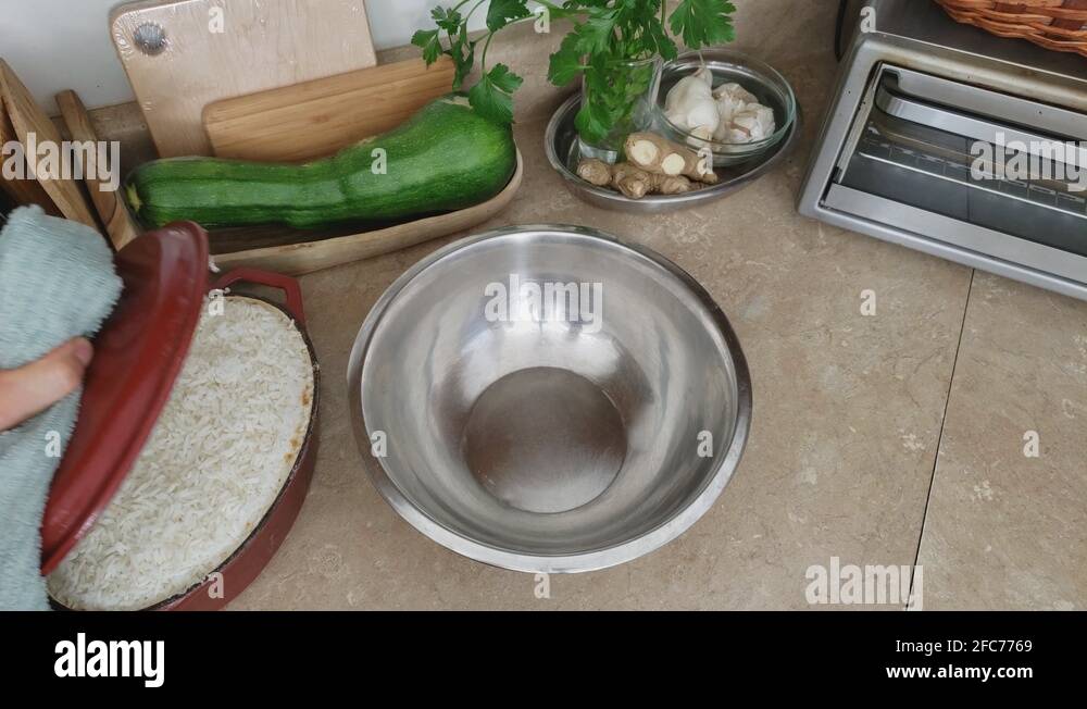 Lifting red pot lid revealing cooked white rice and transferring to ...