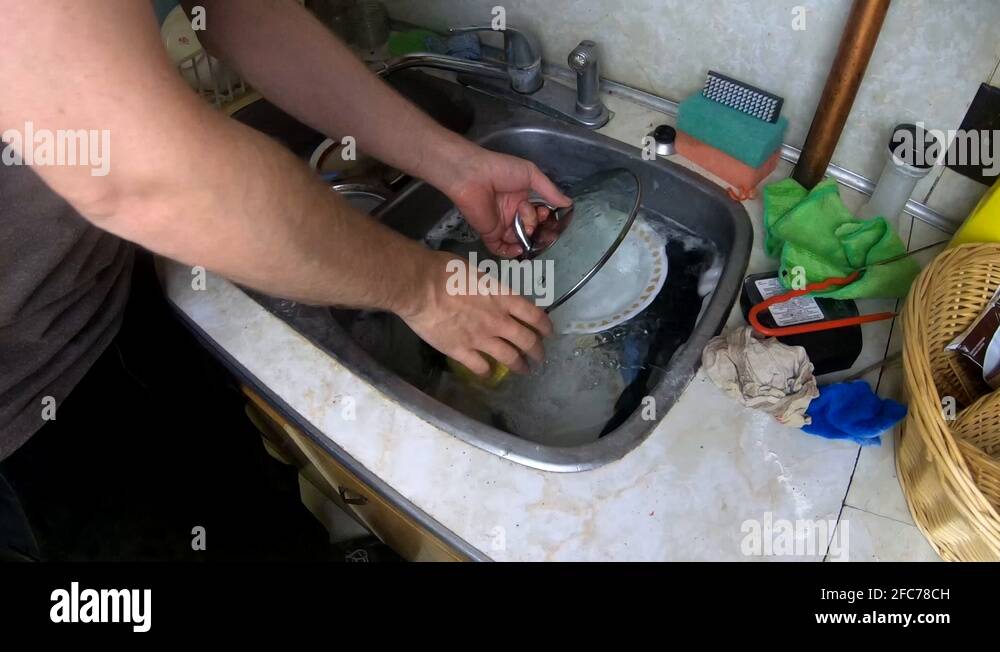Washing dishes in the kitchen with the tap water running Stock Video ...