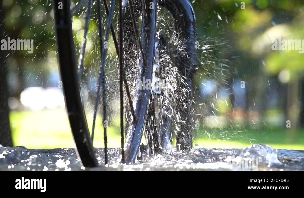 Beautiful fountain and spinning bicycle wheel with water splashing ...
