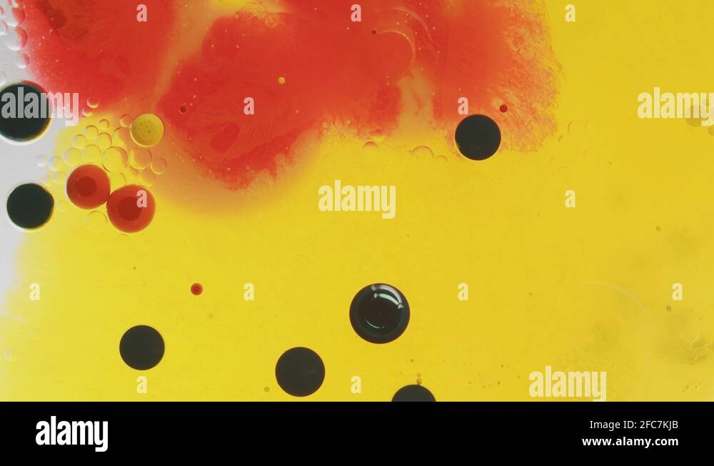 black and red dots are floating in a bright yellow and red liquid ...