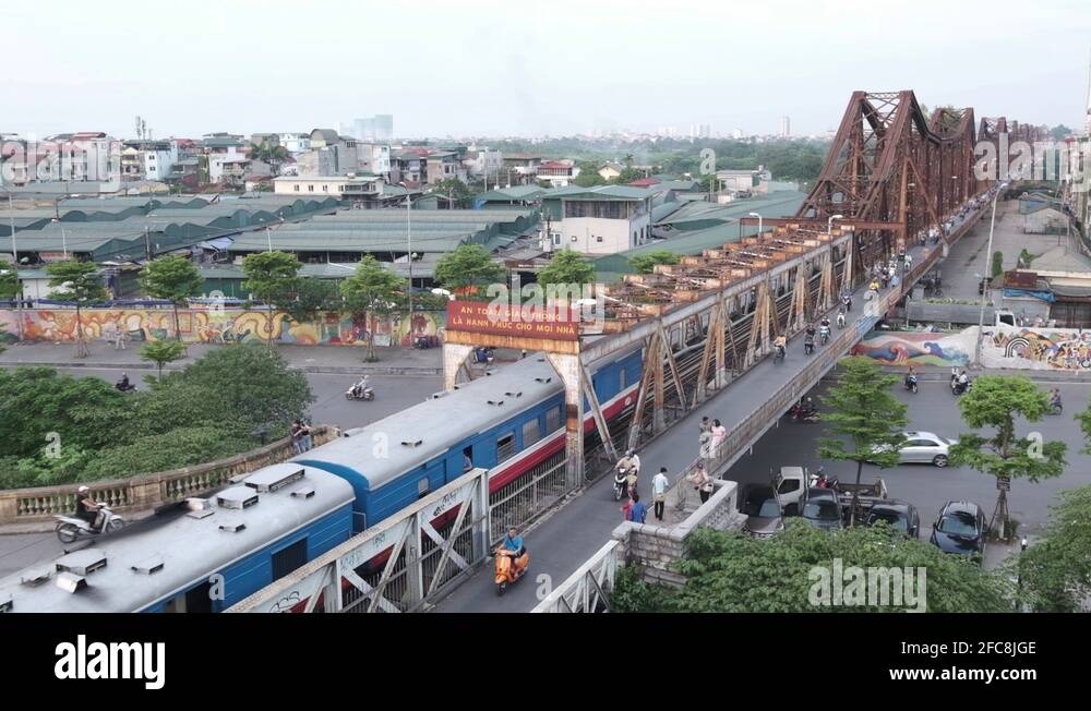 A passenger train carriage emerges from the structure of the Long Bien ...