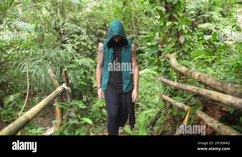 Scary man walking across a narrow bamboo bridge in a jungle. Dangerous ...