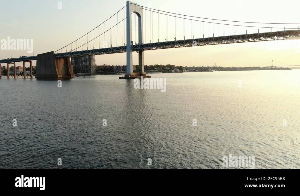 Slow, backwards, aerial of Throgs Neck Bridge revealing a red sail boat ...