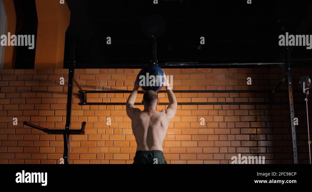 Muscular man in Gym athlete squats and throw the ball, muscle training ...