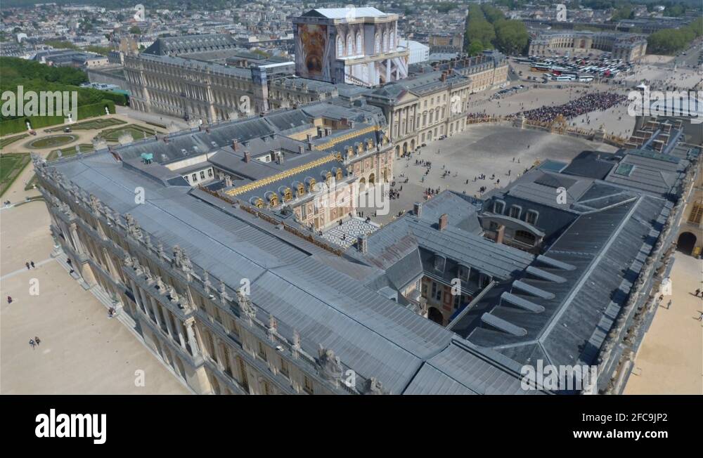 Drone rising over Palace of Versailles with large crowd of visitors ...
