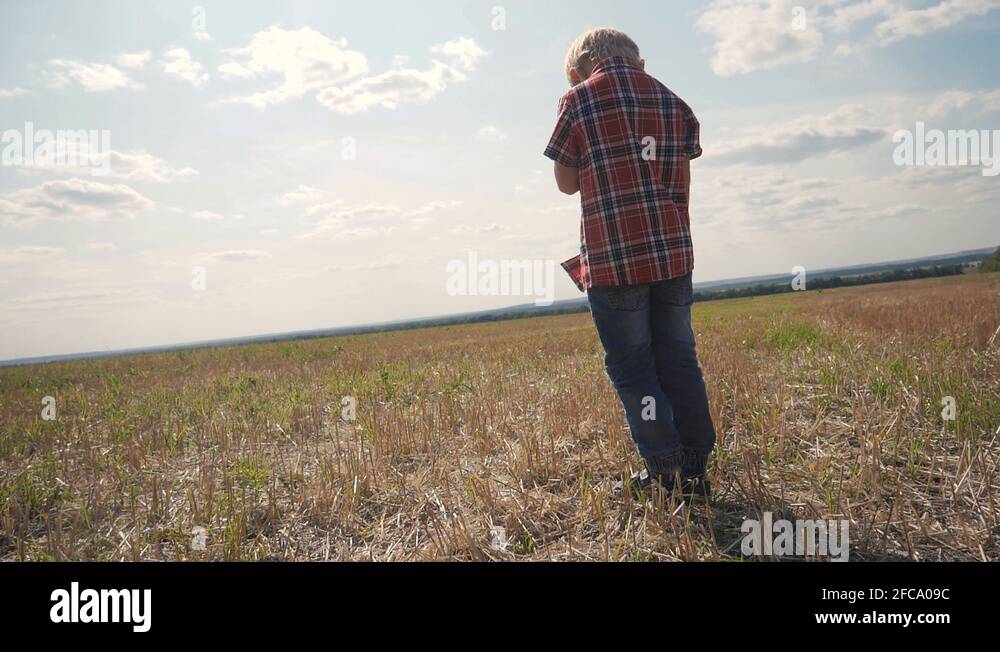 sad little boy stands with his back on nature covered his face with his ...