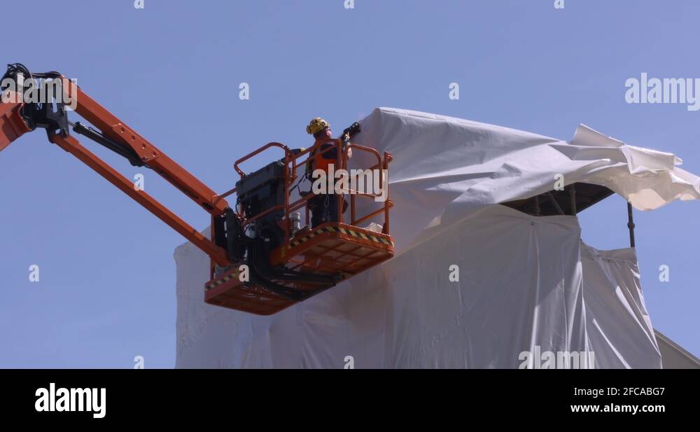 Scaffolder on elevated work platform shrinks wrap to a scaffolding ...