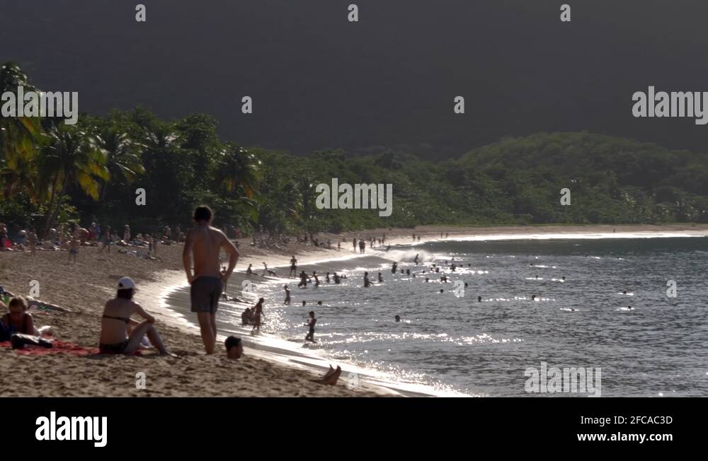 Shot of kids running on a crowded beach and jumping into the water ...