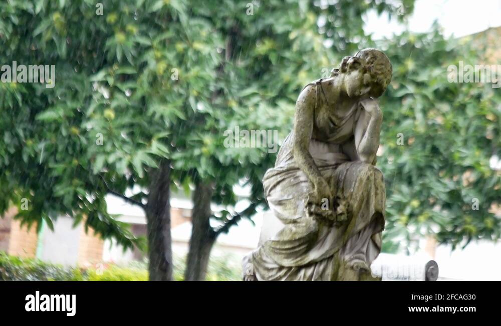 Female statue headstone in rainy cemetery. Angelic decorative carving ...