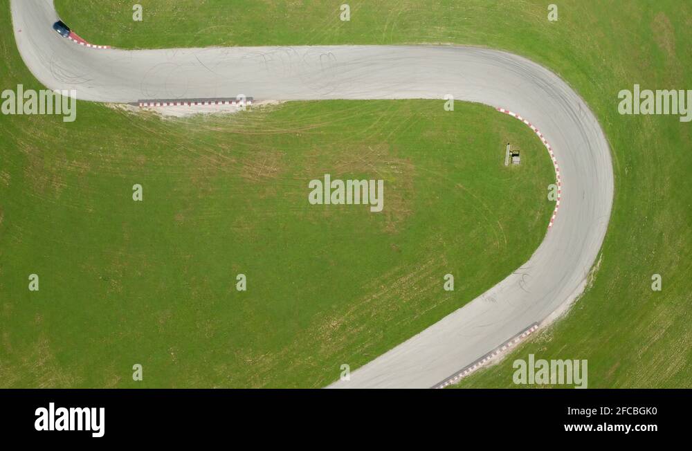 Single race car takes a sharp corner on race track. Topdown aerial view ...