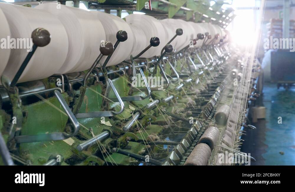 Metal machines work with threads at a textile factory, coiling them ...