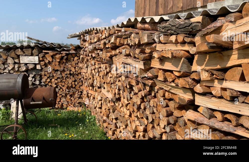 Steel drum log burner next to stacked woodpile storage area Stock Video ...