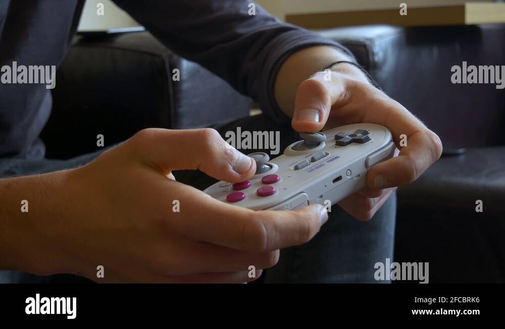 Focused young man playing a video game using a wireless controller ...