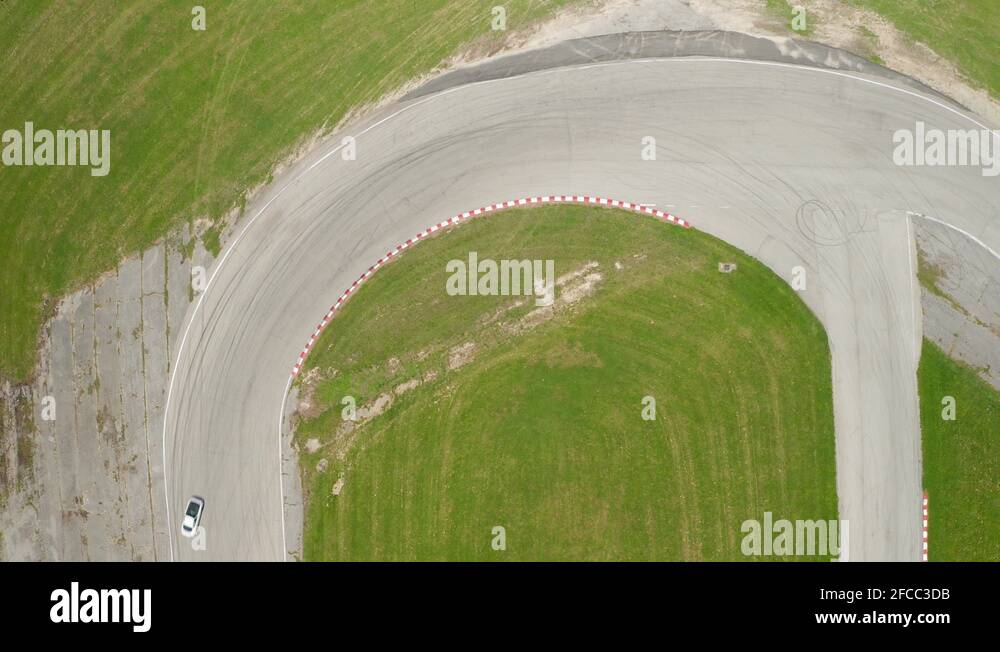 Two racecars take a sharp 90 degree turn on a racetrack. Topdown aerial ...